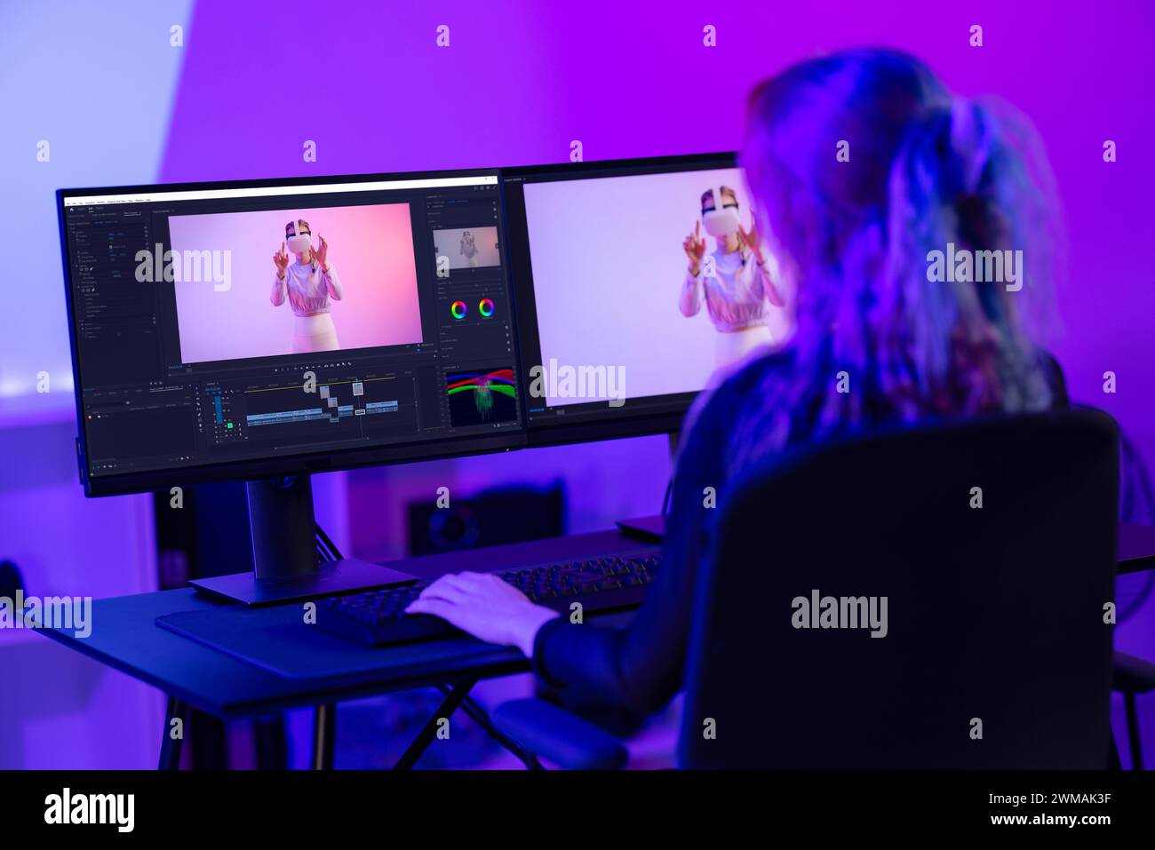Creative digital artist editing video at work amidst neon lights Stock ...
