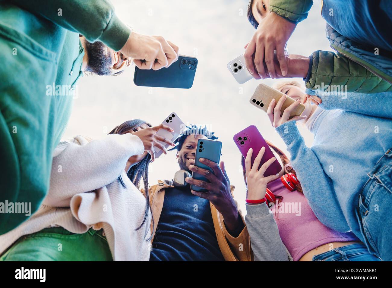 Group of young adults engaged with their smartphones sharing content ...