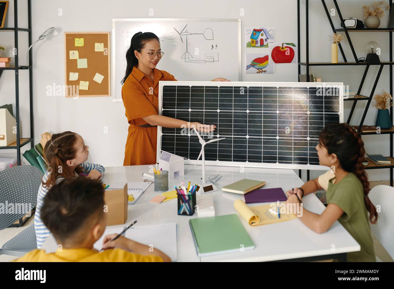 Positive teacher showing children solar panel and explaining how it ...