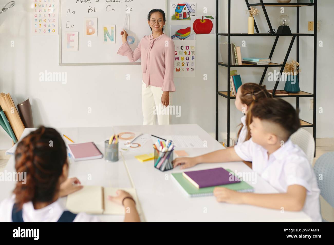 School kids listening to teacher explains how pronounce letters of ...