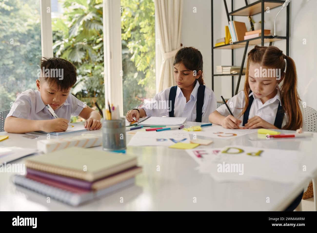 School kids practicing writing letters of English alphabet Stock Photo ...