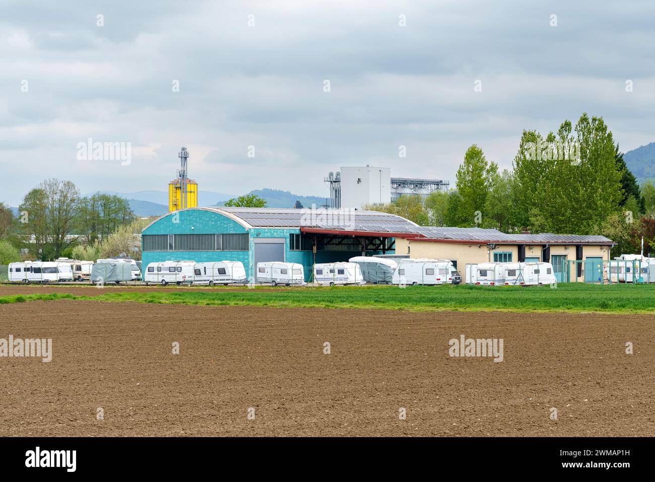 A fleet of white semi-trailer caravans is parked orderly next to a ...