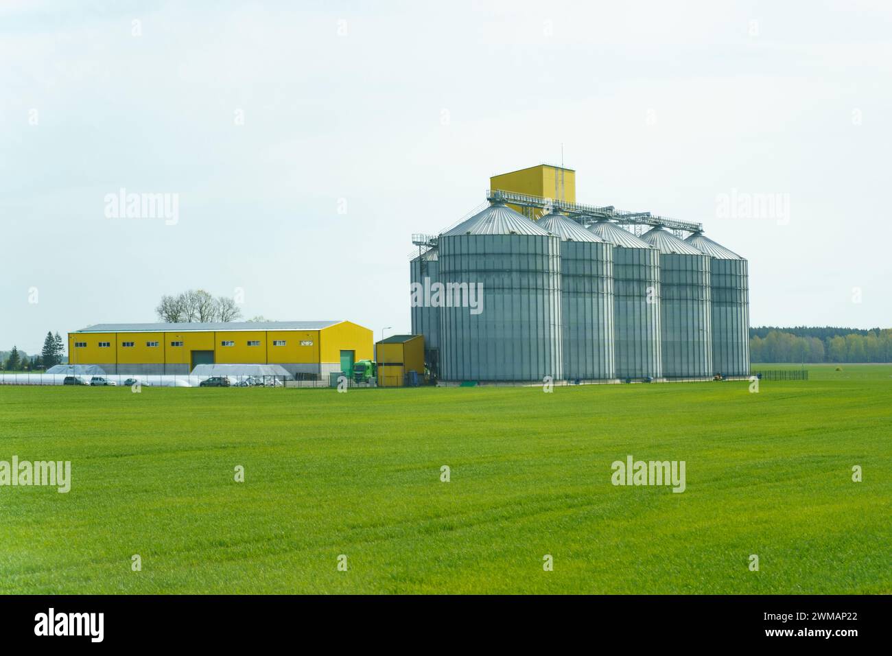 A modern agricultural setup featuring tall metal grain silos connected ...