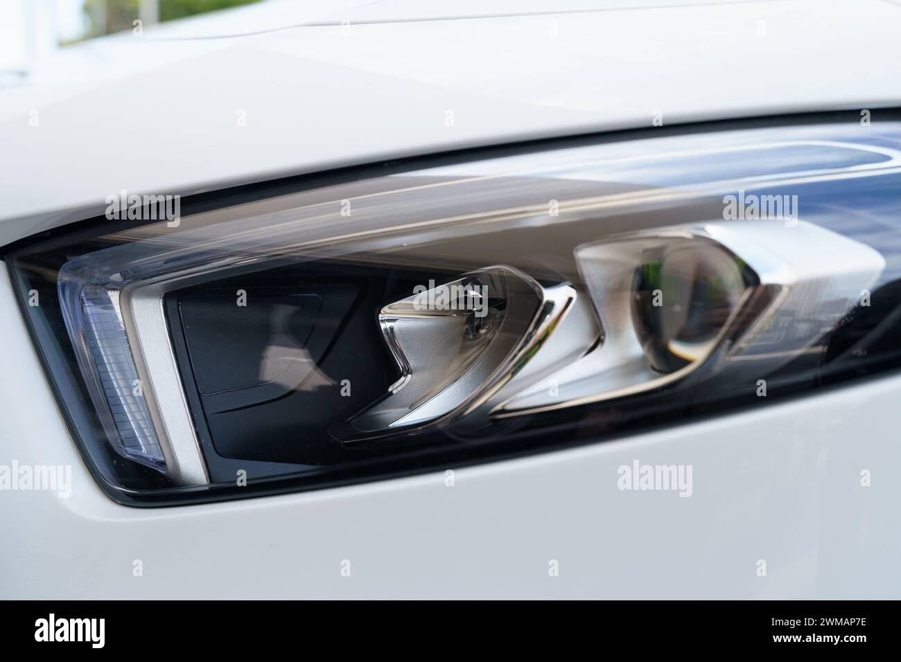 A detailed close-up view of a modern cars headlight, showing the intricate design and textures ...