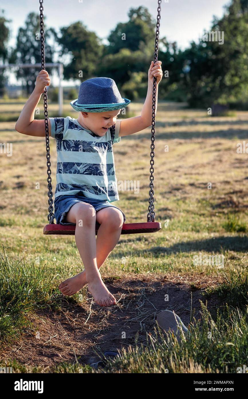 Cute child swinging on a swing. Crazy playful child swinging on playground Stock Photo - Alamy