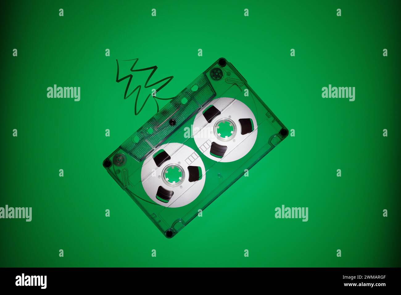 Transparent plastic audio cassette on green acrylic glass illuminated ...