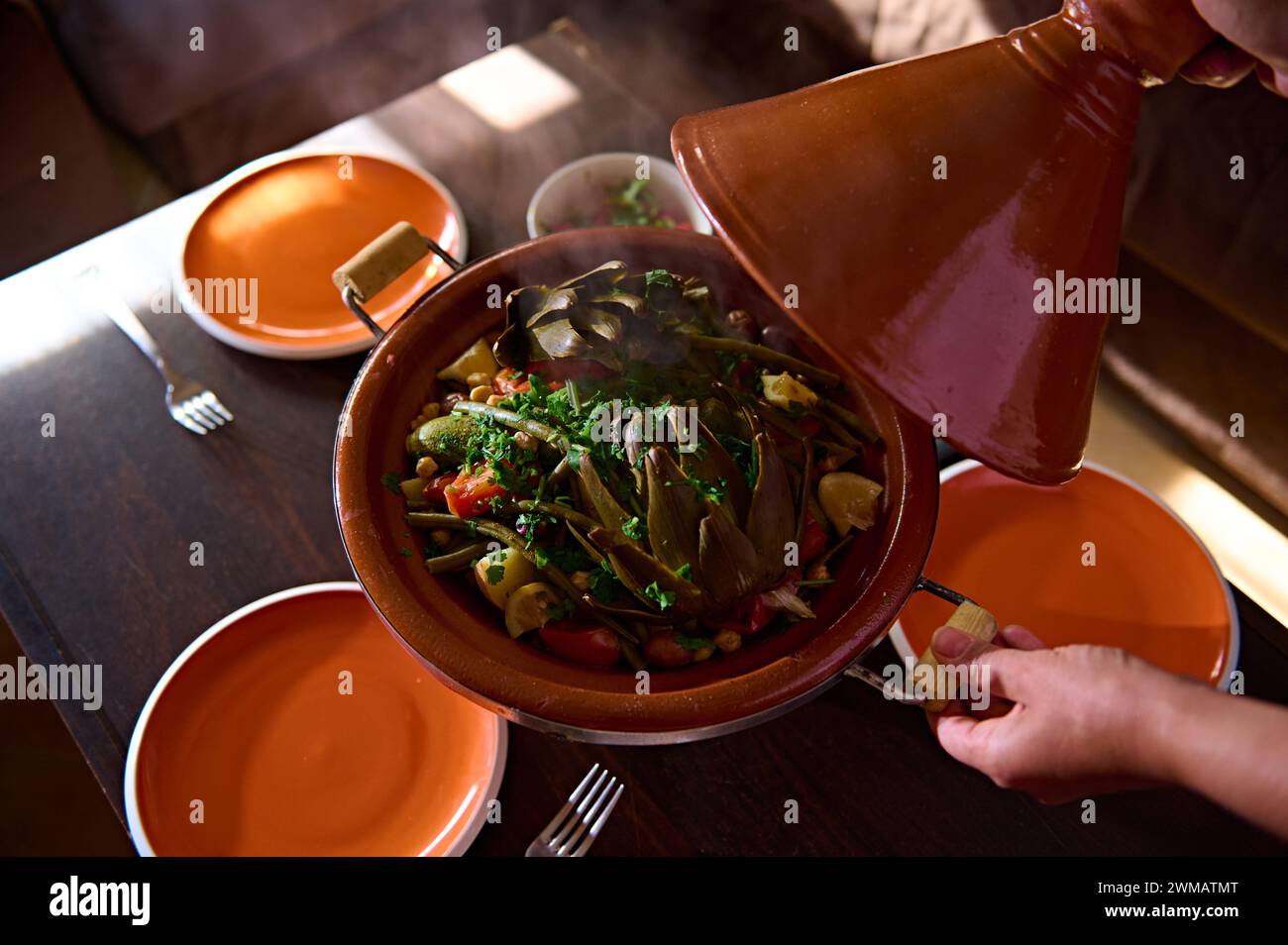 Steamed artichoke in Moroccan tagine clay pot. Top view of a housewife ...