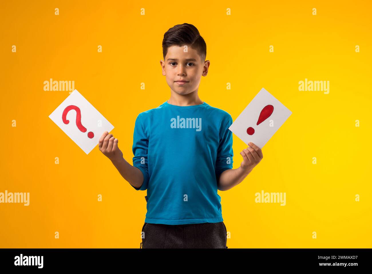 Portrait of kid boy holding question mark and exclamation point card in hand. Education and ...