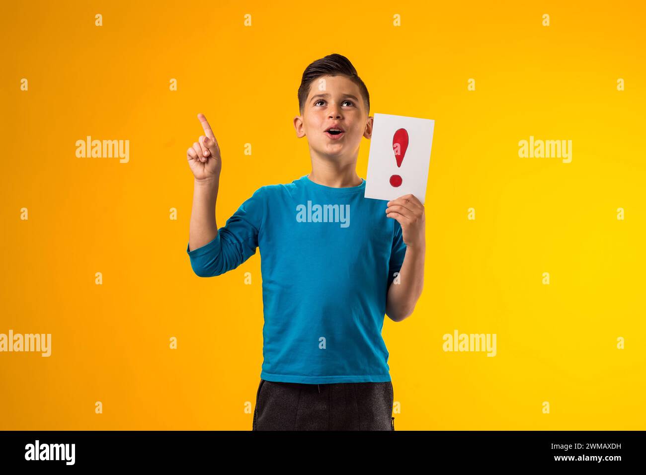 Portrait of surprised kid boy holding exclamation point card and ...