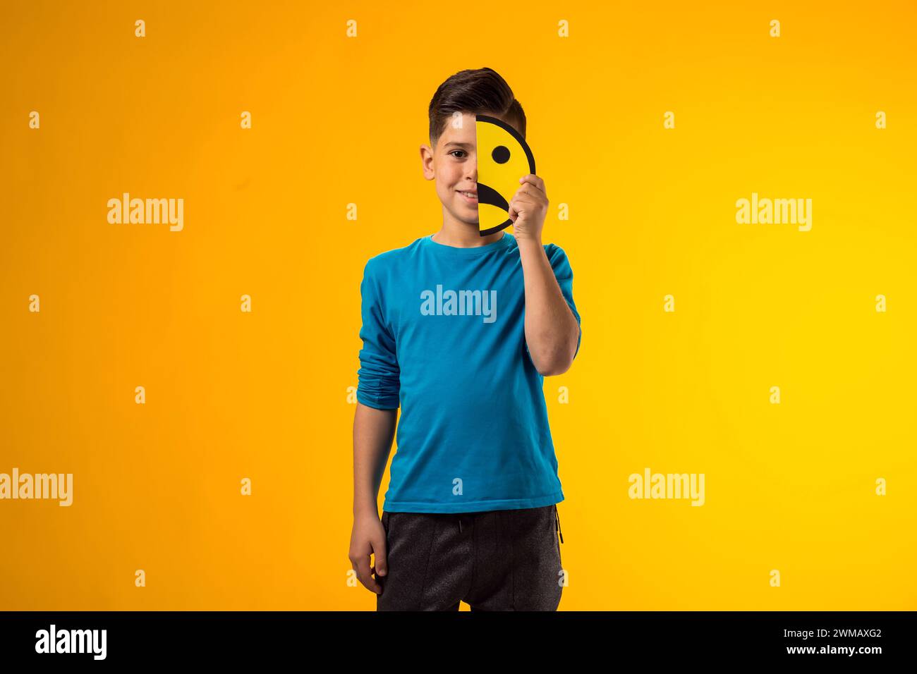 Portrait of child boy holds emoticons on half face with sad emotions ...