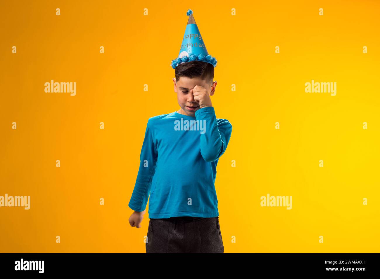 Portrait of crying kid boy wearing blue cone hat having mournful upset ...