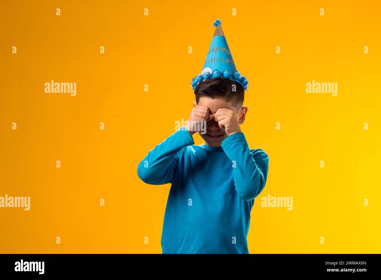 Portrait of crying kid boy wearing blue cone hat having mournful upset ...