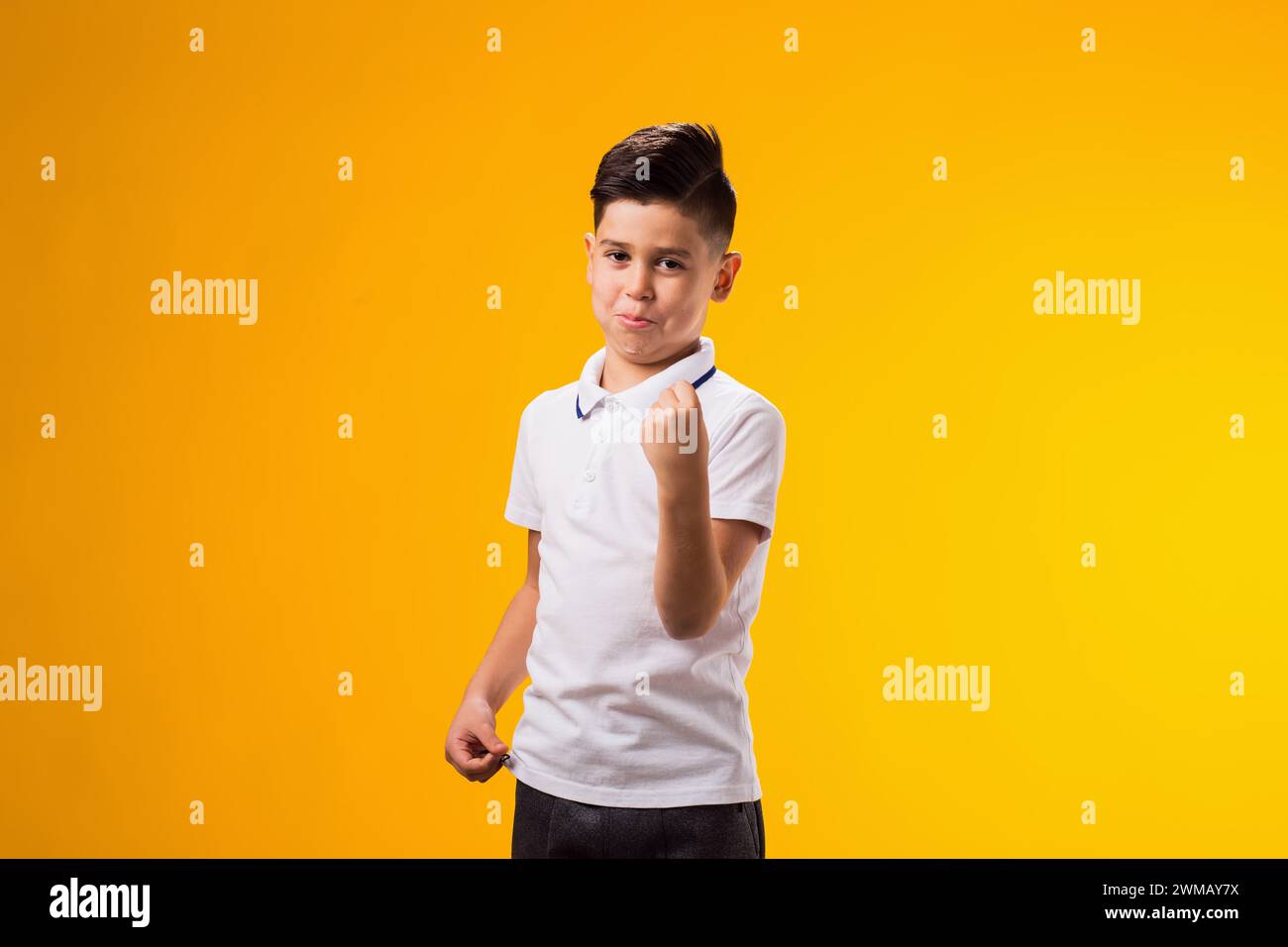 Portrait of angry child boy showing fist at camera over yellow ...