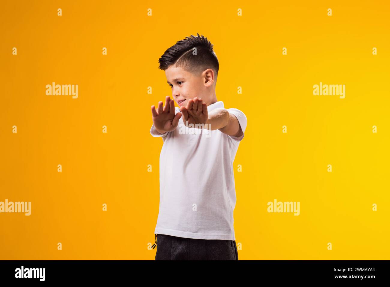 Portrait of child boy showing stop gesture on yellow background ...