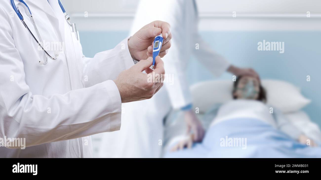 Doctor taking a patient's temperature using a digital thermometer, the ...