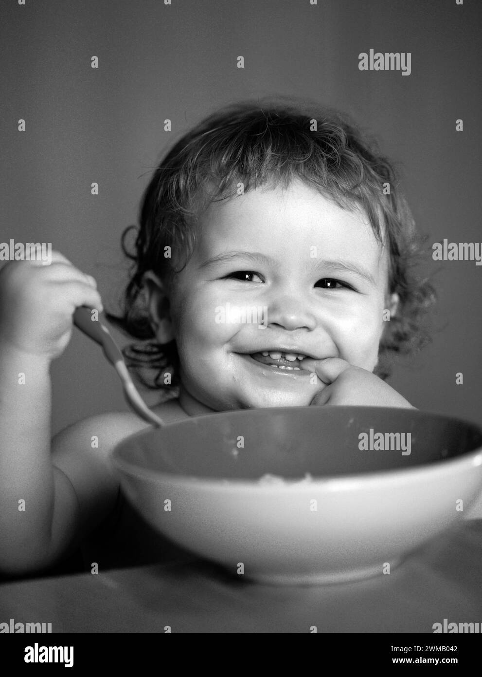 Smiling baby eating food. Launching child eat Stock Photo - Alamy