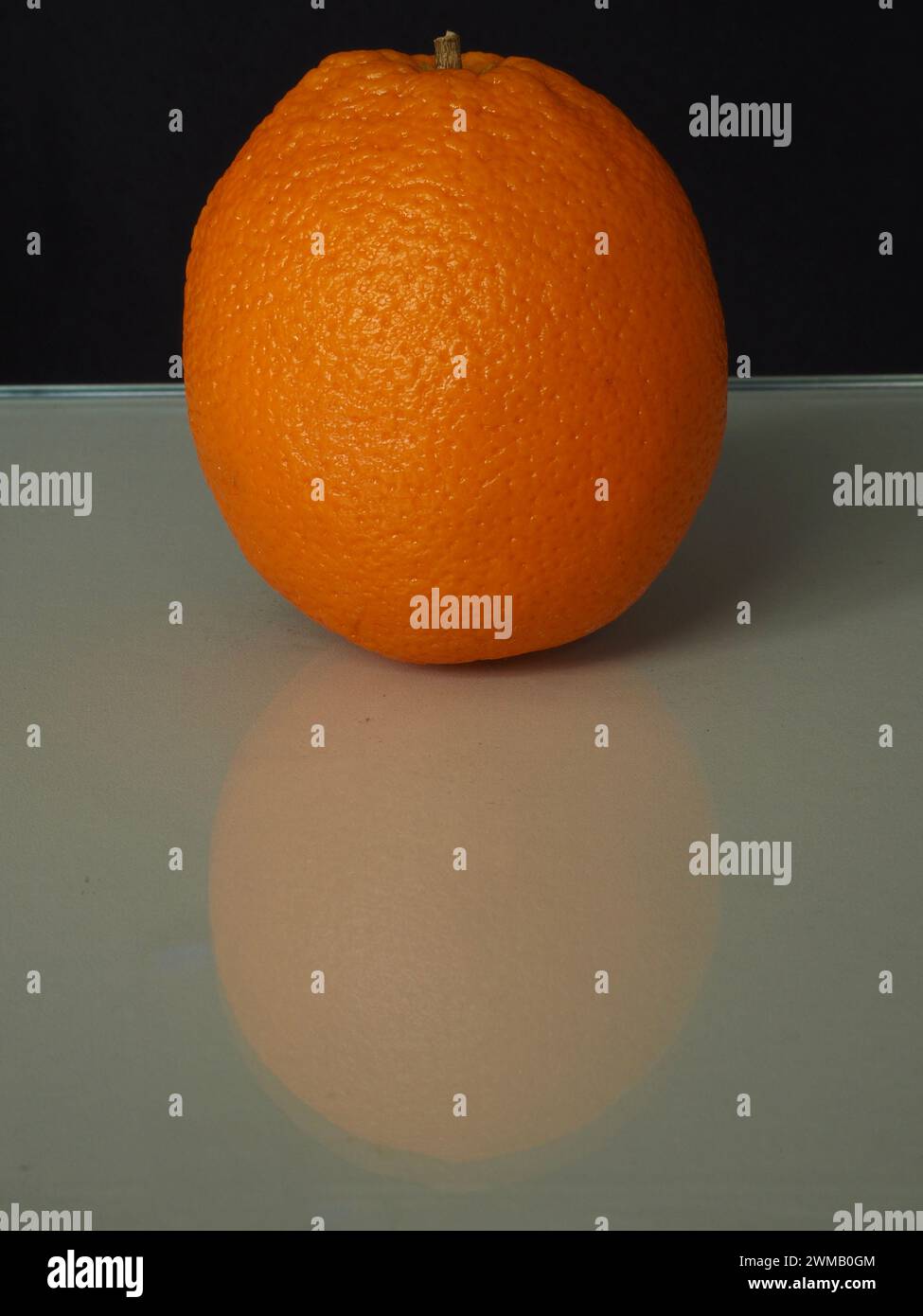 Still life photograph of a single orange with reflection on glass ...