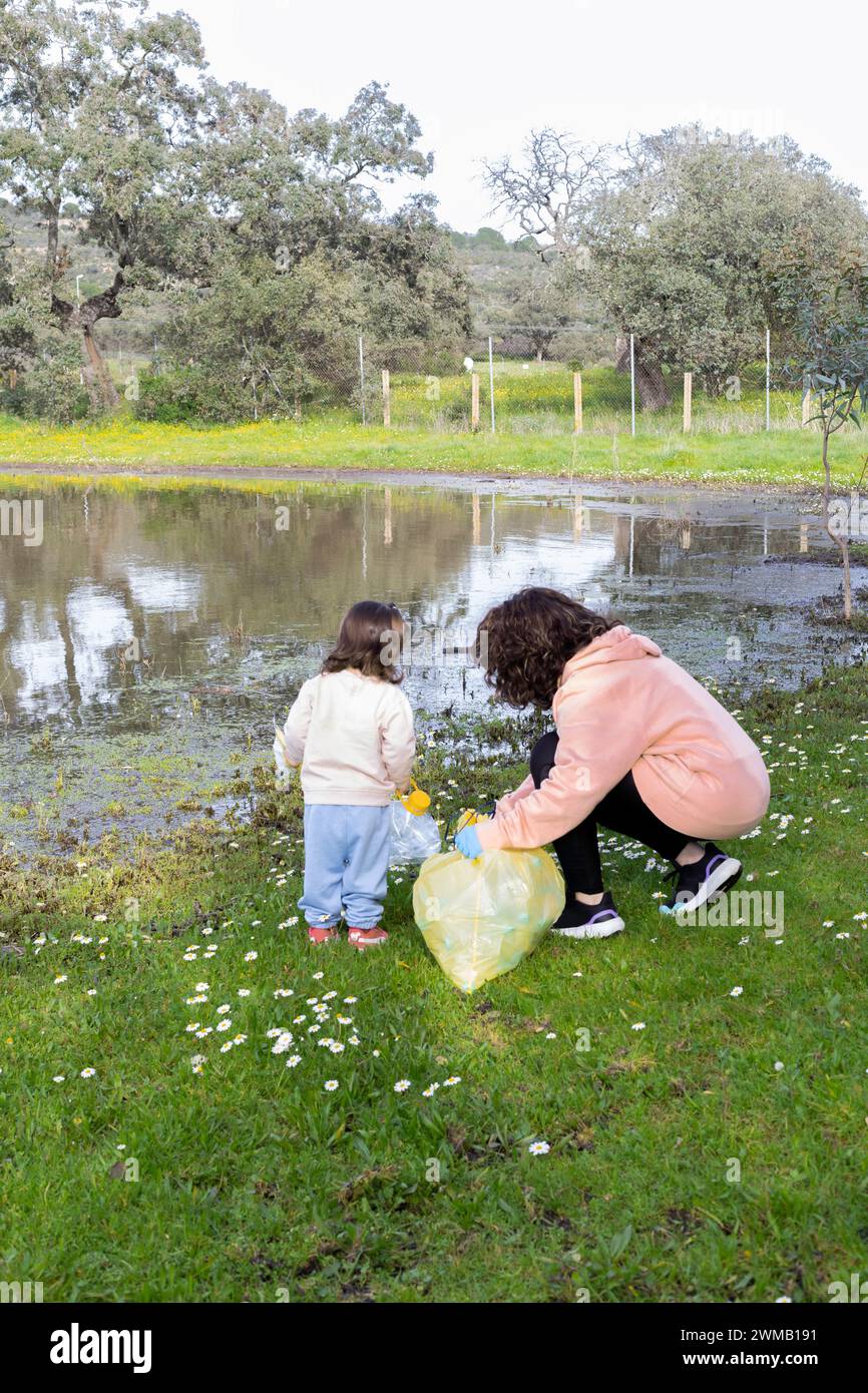 Mother and daughter on a spring day collecting plastic bottles on a ...