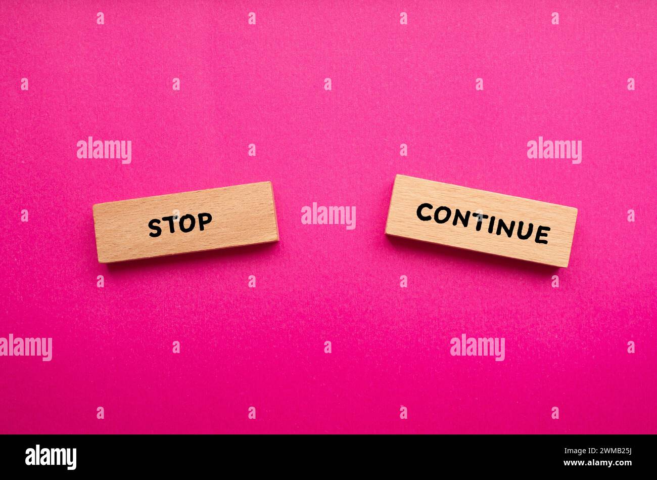 Stop or continue words written on wooden blocks with pink background ...