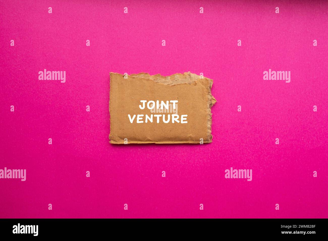 Joint venture words written on torn paper with pink background ...