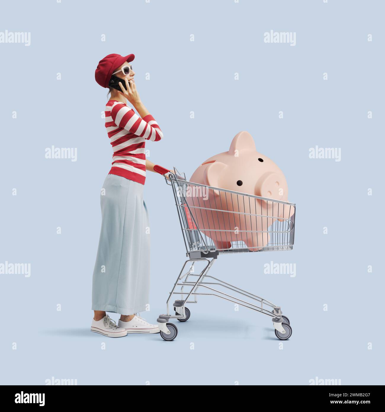 Happy woman having a phone call and pushing a trolley containing a big ...