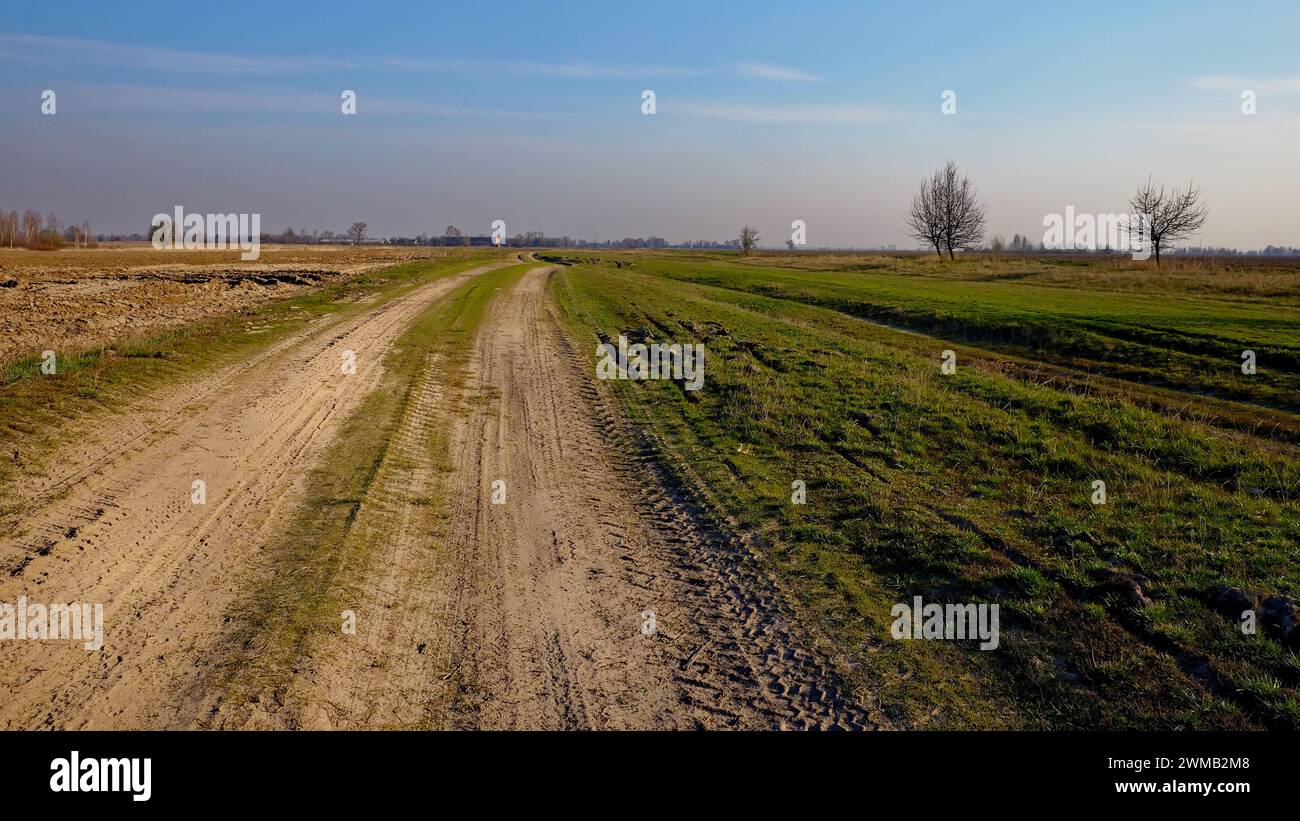 The photo depicts an expansive view of fields intersected by a winding ...