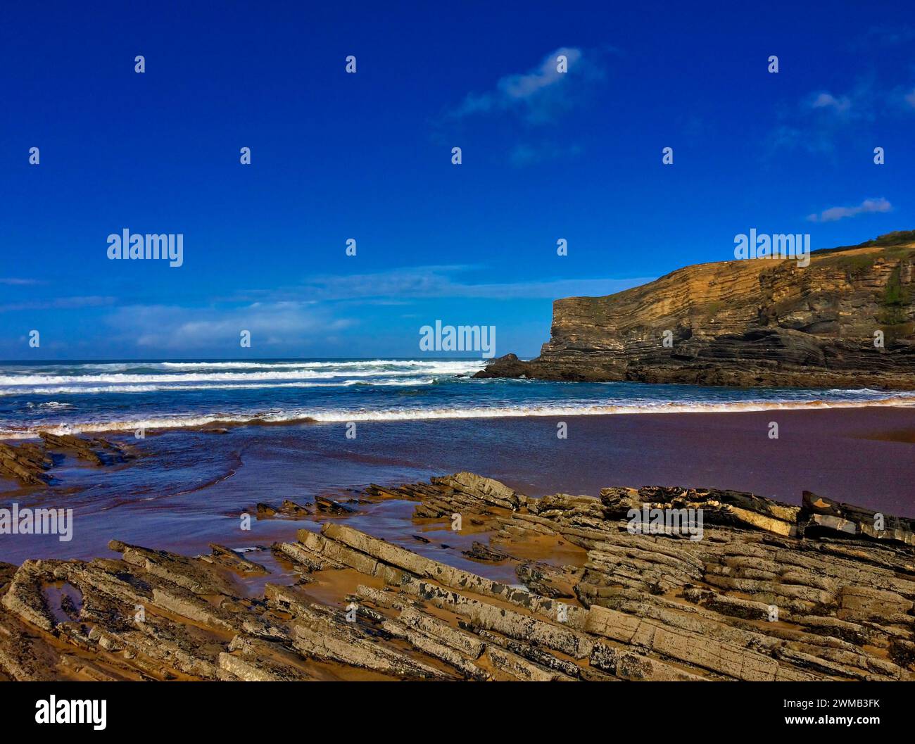 Coastal scene with jagged rocks, turbulent sea waves, and a towering ...