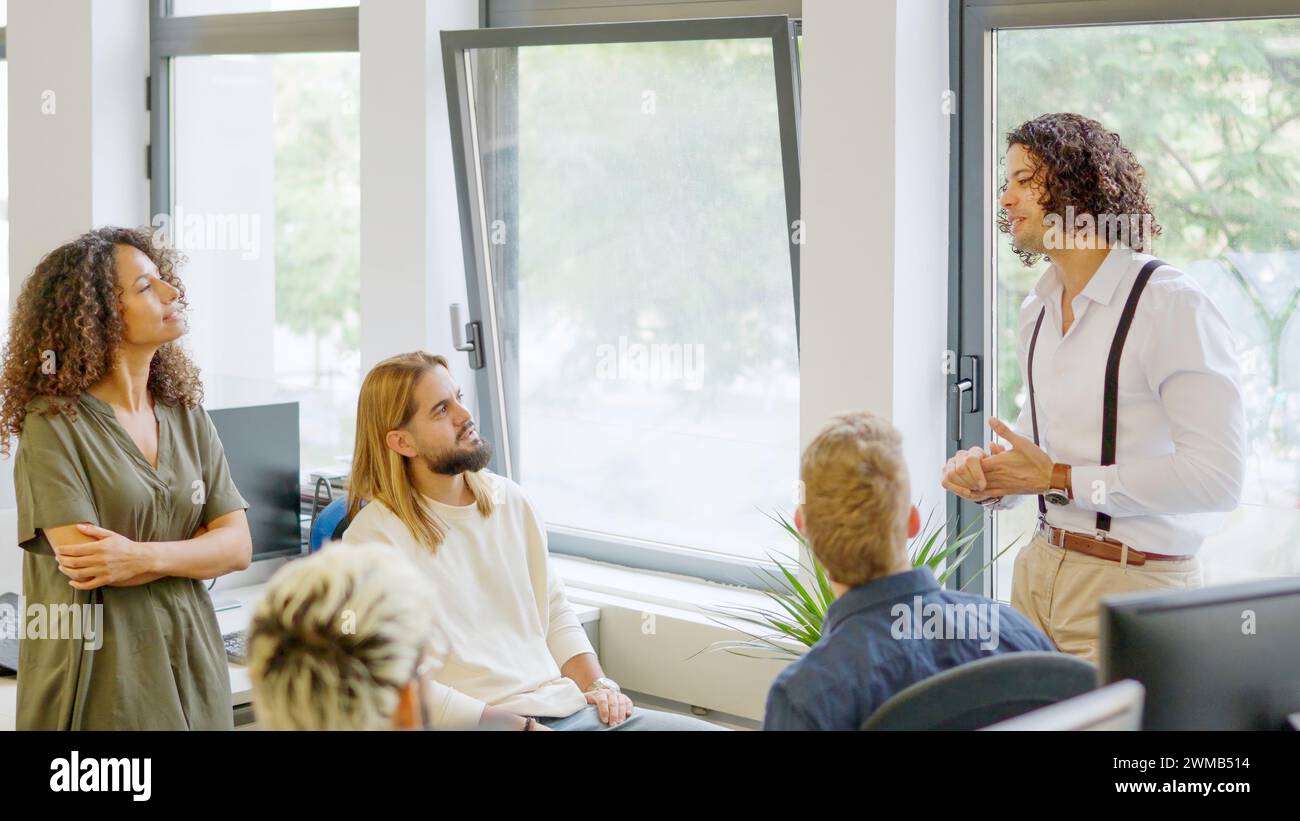 Manager explaining an idea to a friendly team of coworkers Stock Photo ...
