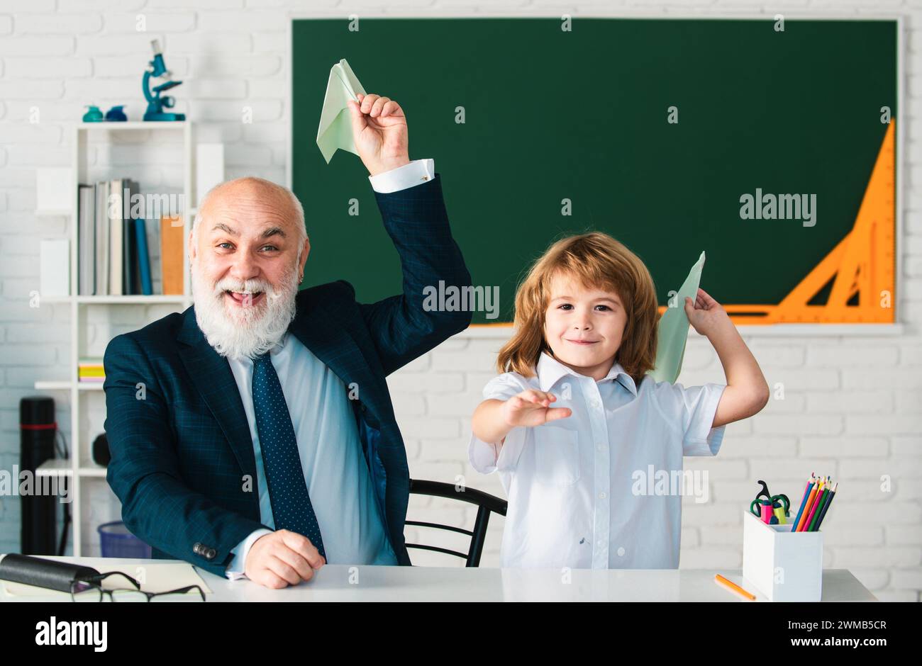 Teacher and school boy with paper airplane. Pedagogue and pupil having ...