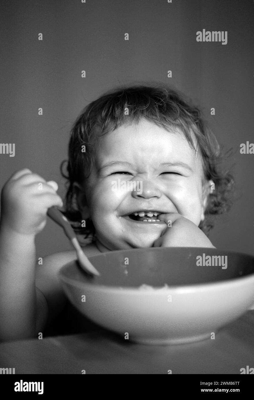 Smiling baby eating food. Launching child with spoon Stock Photo - Alamy