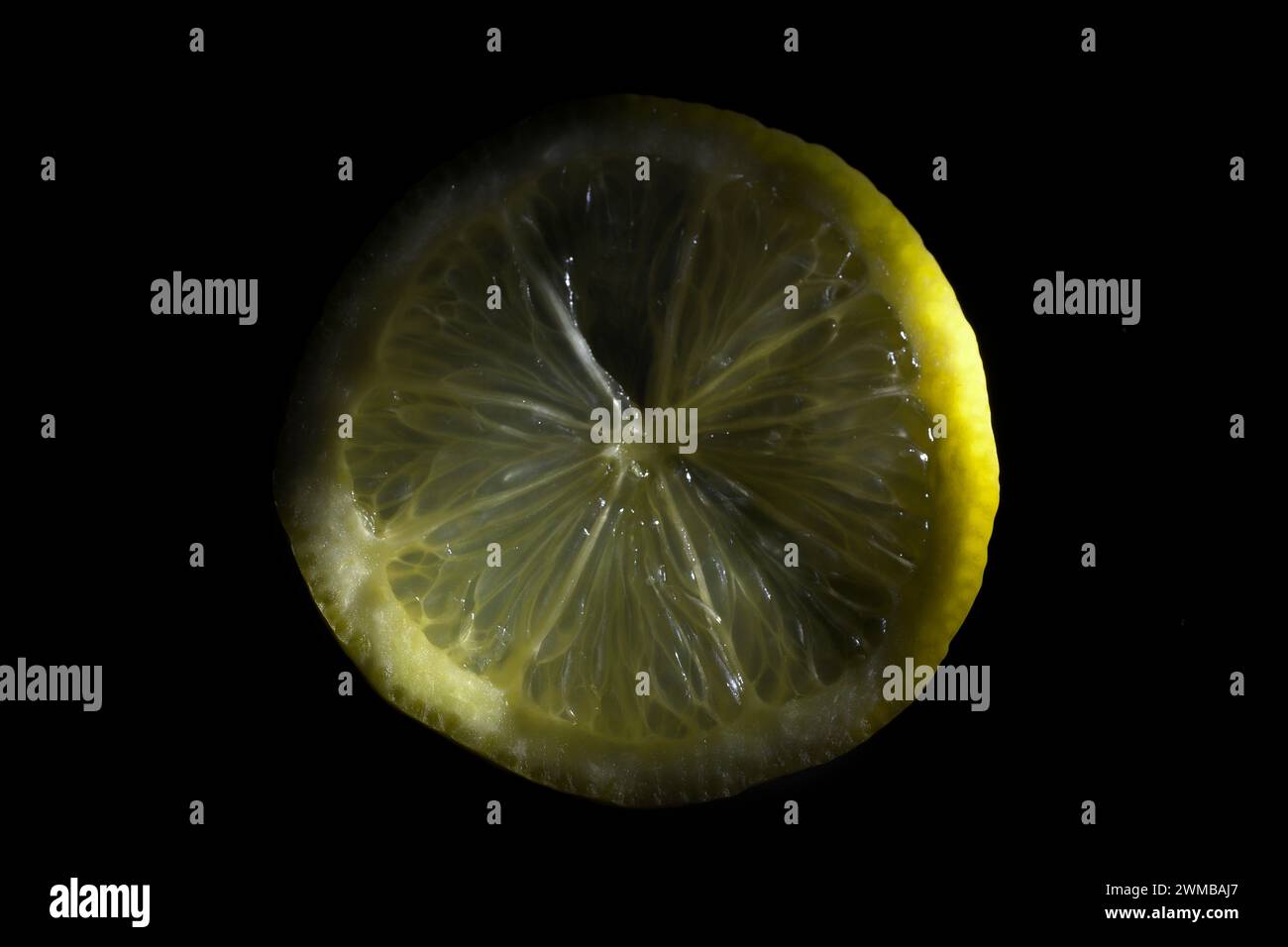 Detail of yellow slice of fresh lemon in half light with black ...