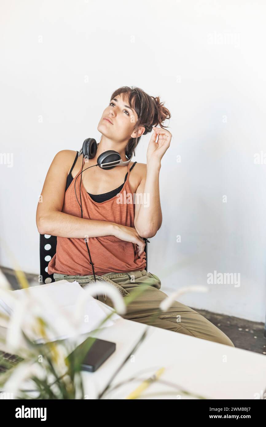 A young woman takes a break from her creative work, her thoughts ...