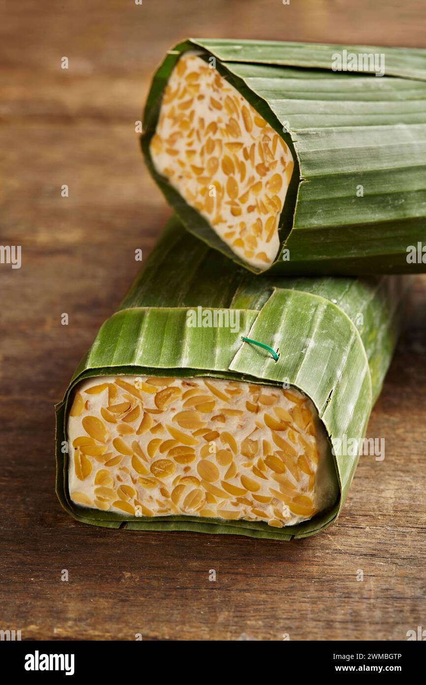 a pile of raw tempeh wrapped in banana leaves. Tempe is a typical ...