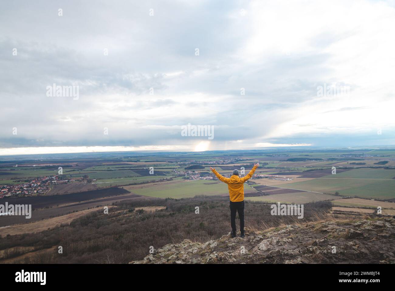 Traveller in a yellow jacket stands on top of Mount Rip, raising his ...