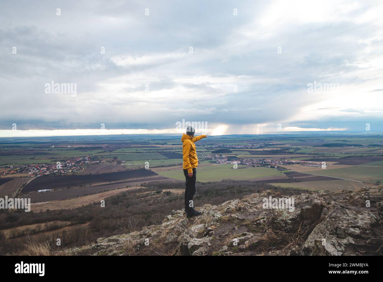 Traveller in a yellow jacket stands on top of Mount Rip and is pointing ...