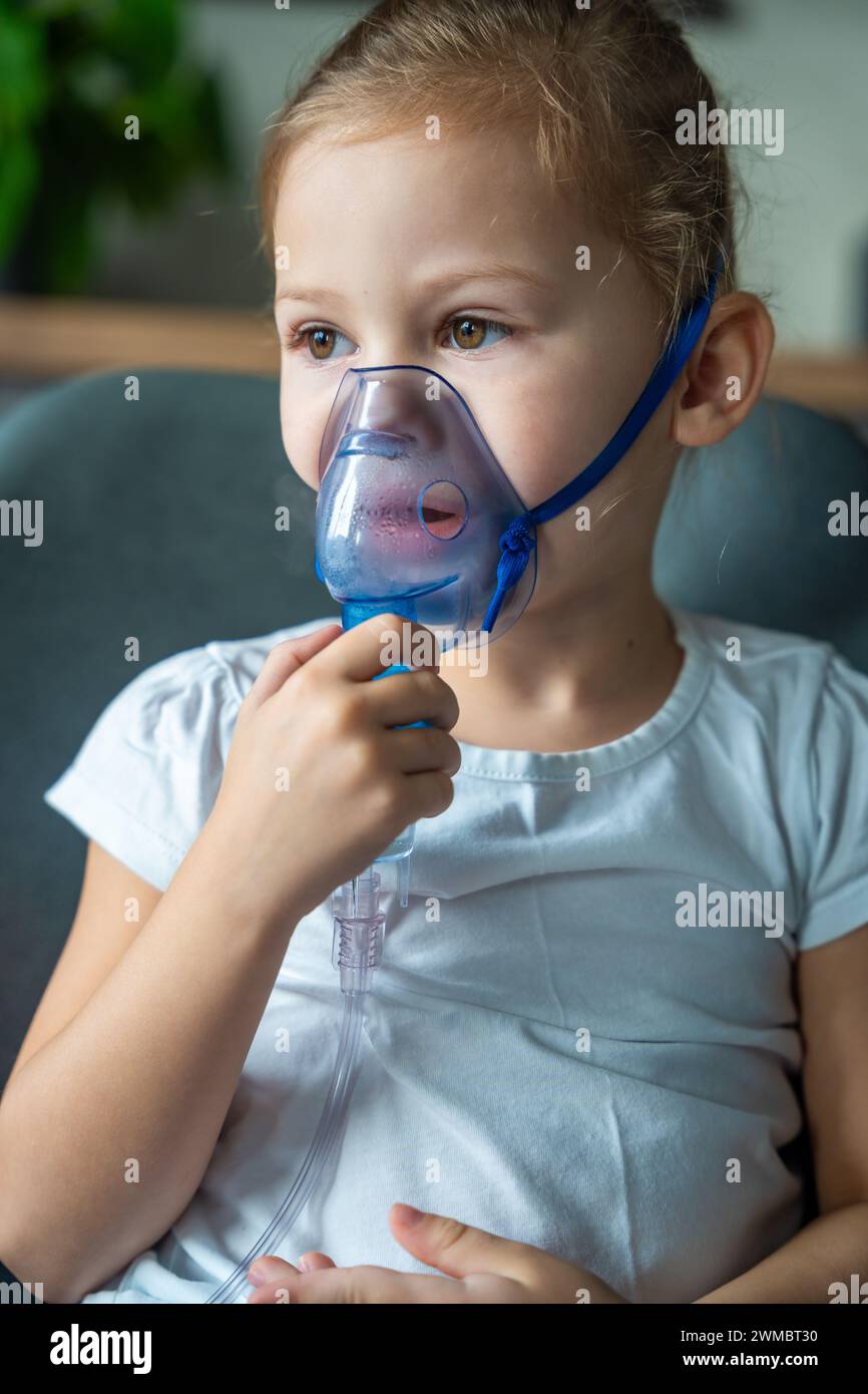 Cute little girl are sitting and holding a nebulizer mask leaning ...