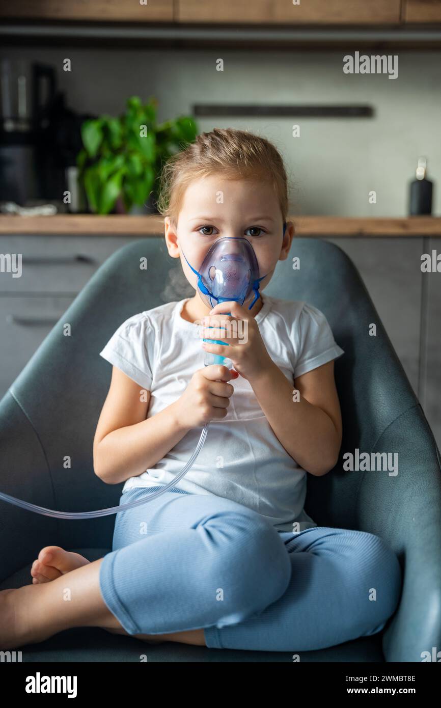 Cute little girl are sitting and holding a nebulizer mask leaning ...