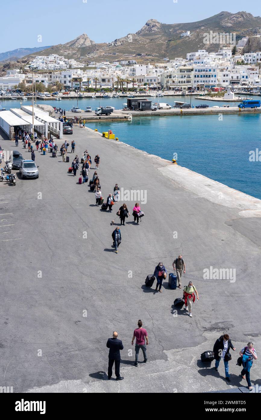 Tourists are walking on the dock of the port of Naxos on their way to ...