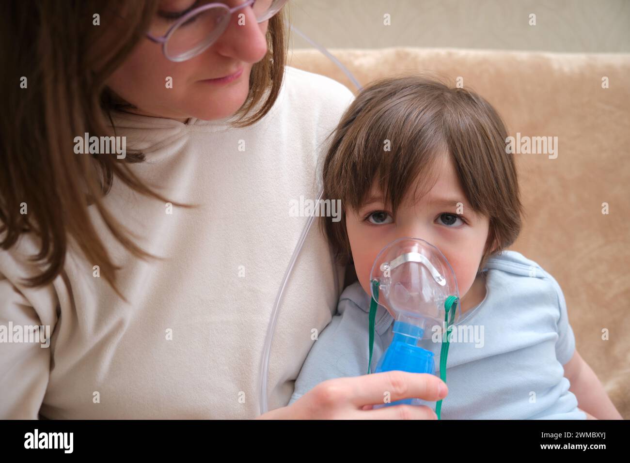 A mother woman with an inhaler helps her child cope with the disease ...