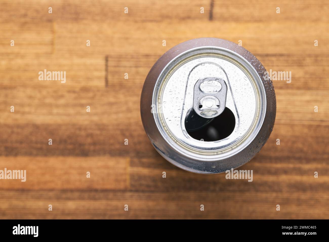 Top-down view of a soda can with water droplets from condensation against rustic wooden table ...
