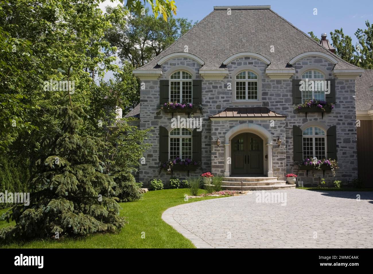 French Manor style natural stone home with paving stone driveway Stock ...
