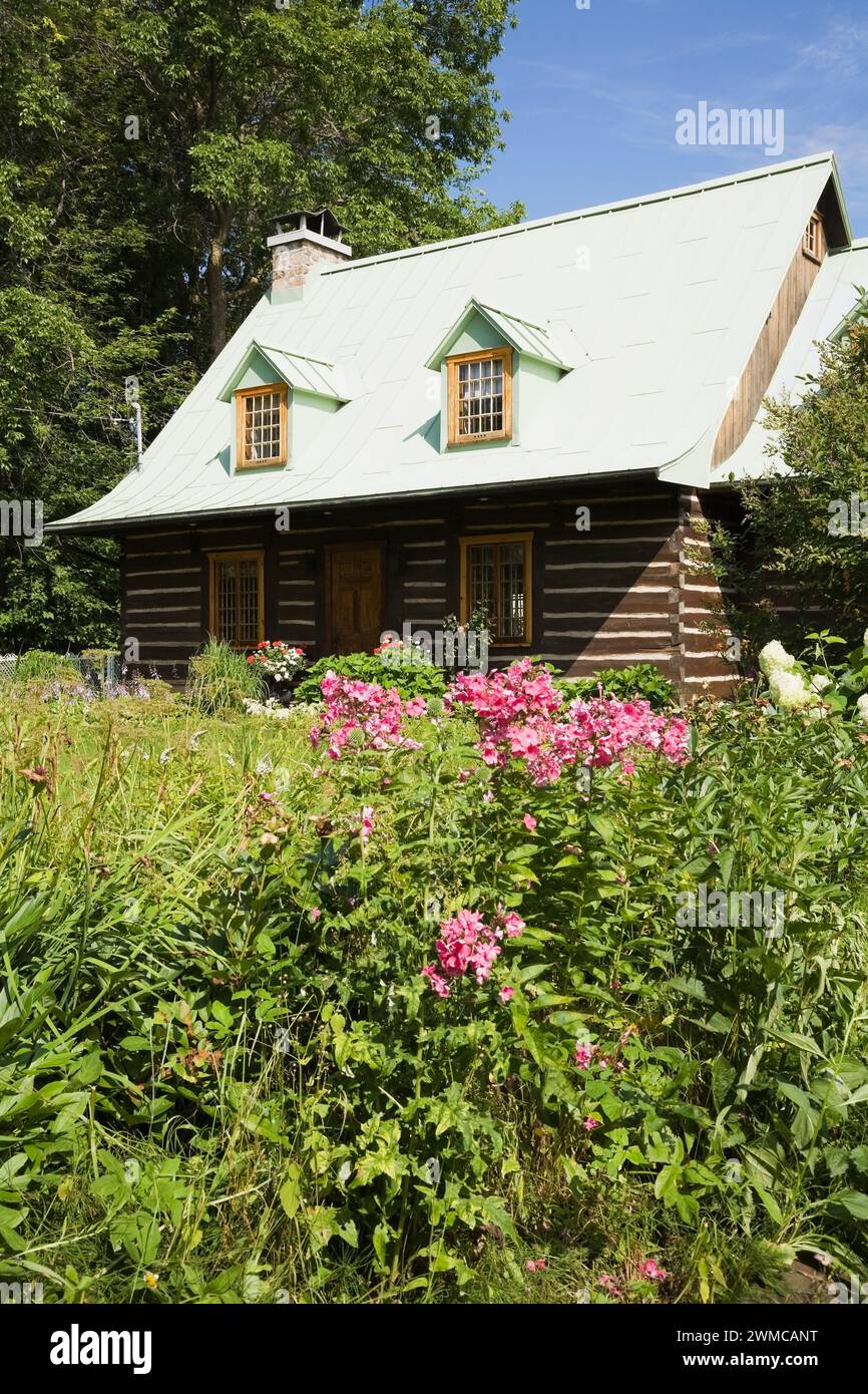 Old log cabin with light green sheet metal roof and landscaped front ...