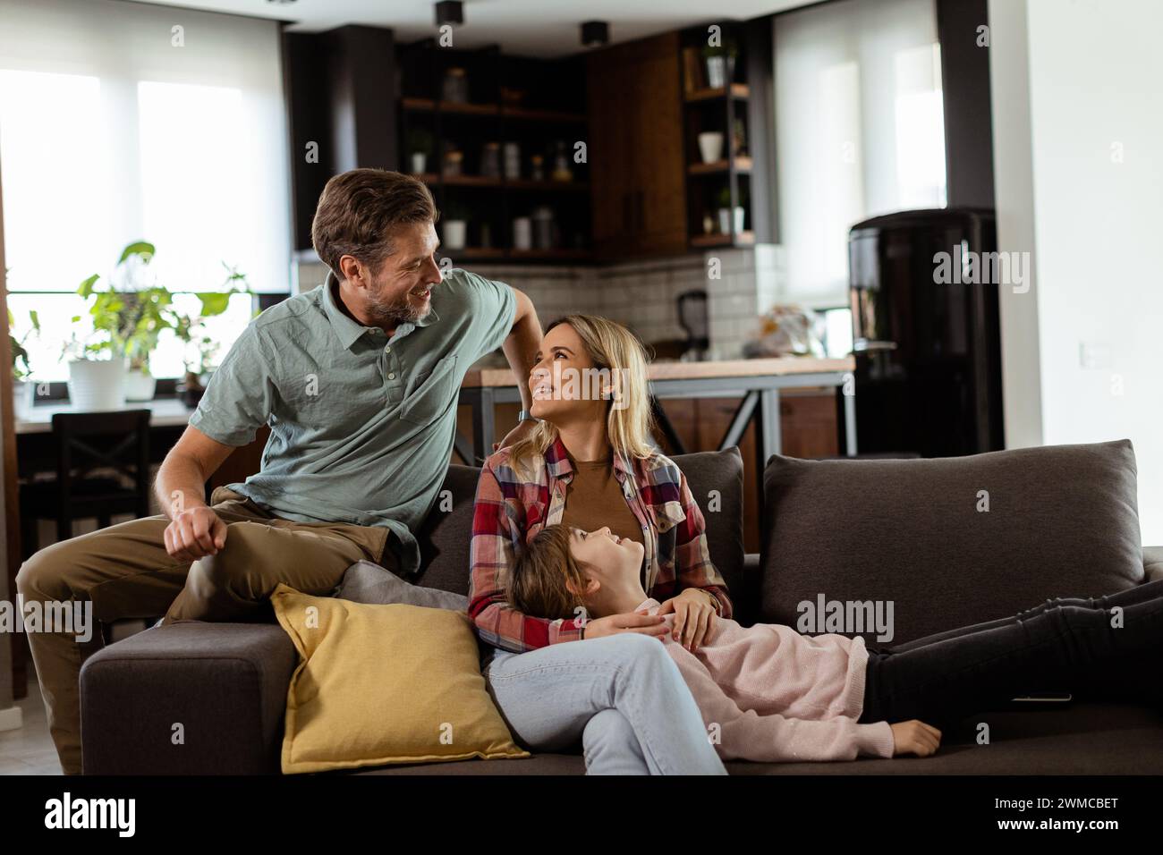 Joyful family shares a relaxed, affectionate moment on the sofa ...