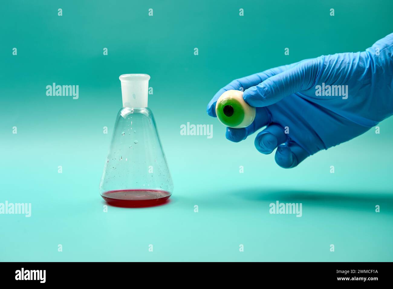Closeup of titration flask with red liquid on green surface and hand of ...