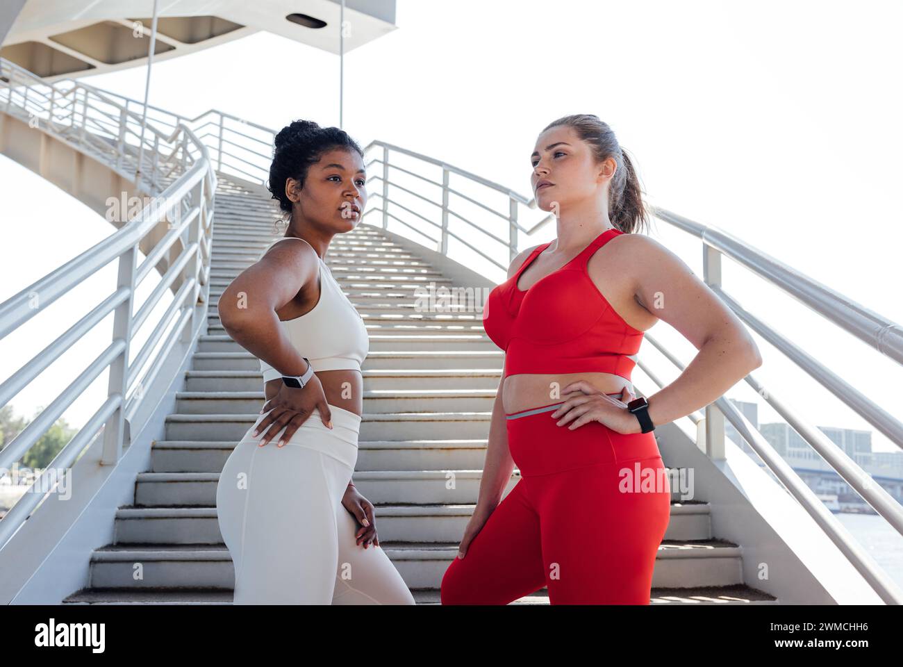 Two confident plus-size women in fitness attire stand together on a ...