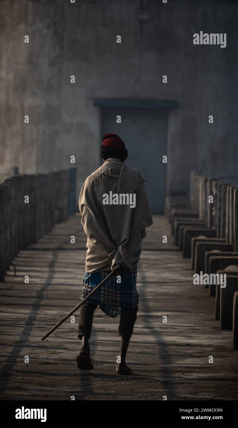 A man walk through the bridge in winter morning holding bamboo stick ...