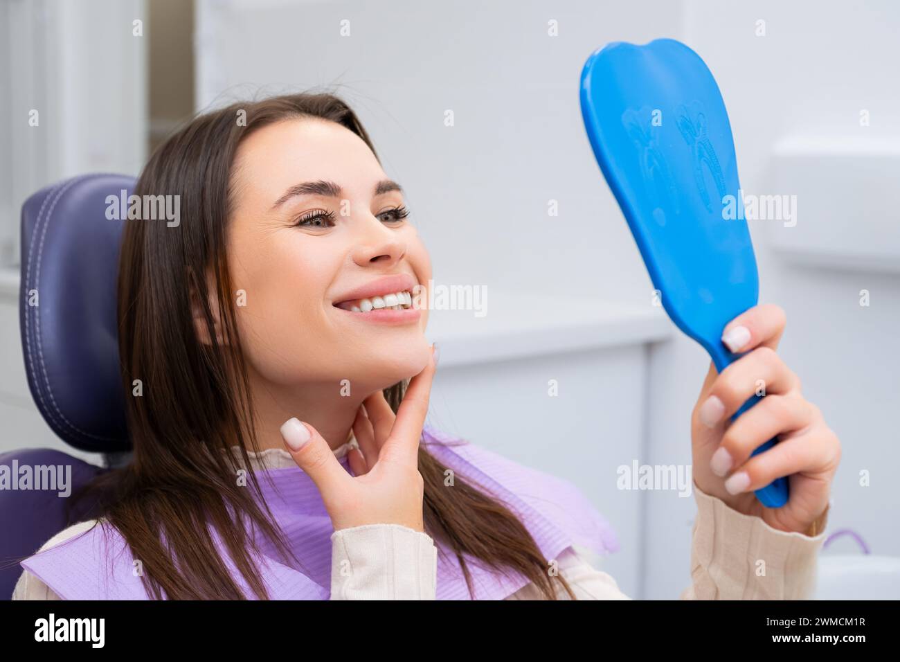 Female patient looks contentedly in the mirror while sitting in the ...