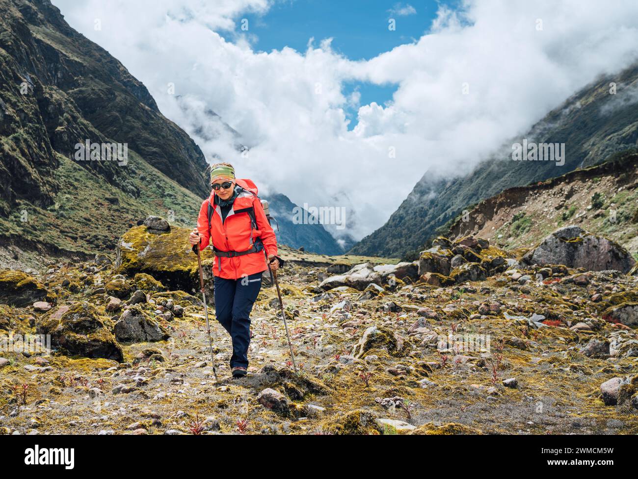 Woman in sunglasses with backpack and trekking poles dressed red ...