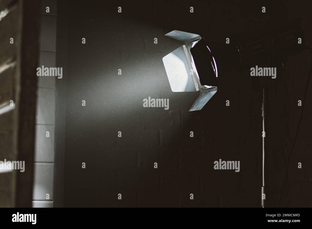 A single studio light shines brightly, casting a beam across the dark ...