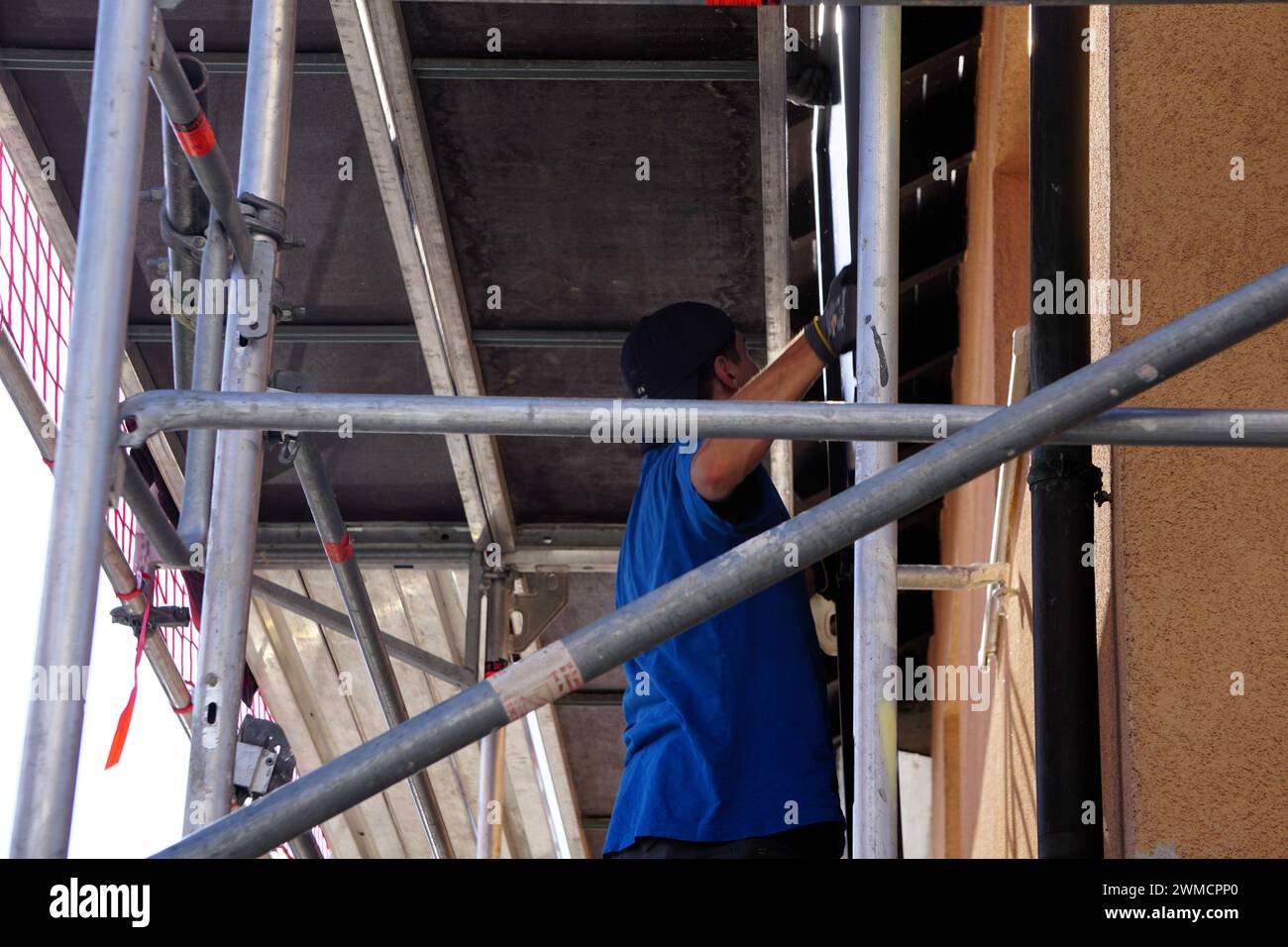 A male worker stands on a scaffold platform while working Stock Photo ...
